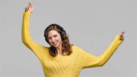 스튜디오에서 회색 배경에 무선 헤드폰을 가진 젊은 여성 그녀는 노란색 스웨터를 입고 설계를 위한 공간을 복사합니다 감정이 있는 개념 14에 대한 스톡 사진 및 기타 이미지