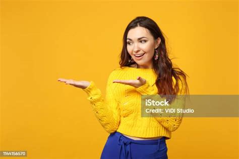 스웨터에 흥분 된 젊은 여자의 초상화 블루 바지 찾고 옆에 고립 된 노란색 오렌지 배경에 스튜디오에서 손을 가리키는 사람들은 진심으로 감정 라이프 스타일 개념입니다 복사