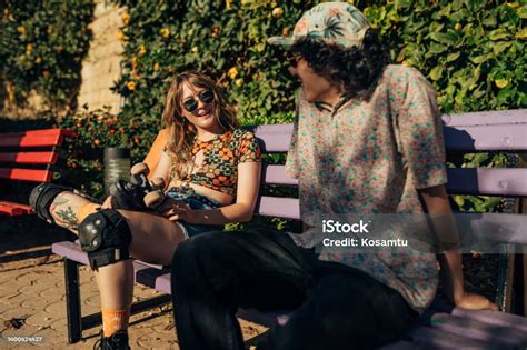 다인종 남성이 롤러 스케이트를 타는 여자 친구 옆의 공원 벤치에 앉아 있습니다 말하기에 대한 스톡 사진 및 기타 이미지 말하기 보라색 사람들 Istock