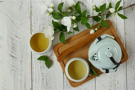 자스민 추출 물이 함유 된 유기농 차 나무 쟁반에 아시아 스타일의 가벼운 녹색 주전자와 컵과 초라한 세련 된 나무 바탕에 흰색 재 스민의 분출 0명에 대한 스톡 사진 및