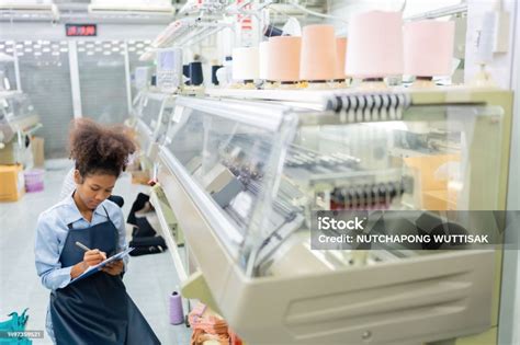 미국 여성 디자이너 직공 앉아서 제품 디자인 주문 체크리스트를 적어 두십시오 그녀 근처에는 작동하는 재봉틀과 여러 가지 빛깔의 실이 있었다 대규모 직조 산업에서 20 24