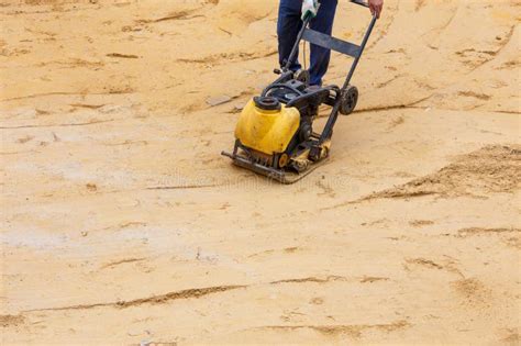 Worker Using Vibratory Plate Compactor For Compaction Sand During Path Construction Stock Photo