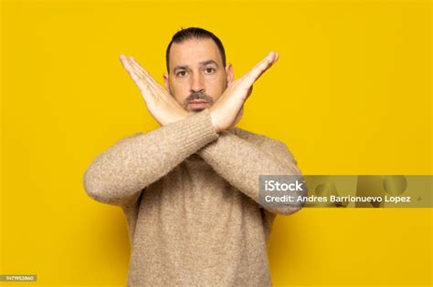 절대 안돼 절대적으로하지 터틀넥에 수염을 기른 히스패닉 남자의 초상화는 교차 손으로 X 기호를 보여줍니다 노란색 스튜디오 배경에 격리 거절에 대한 스톡 사진 및 기타 이미지