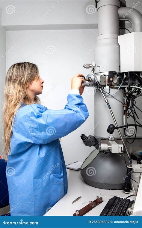 Young Female Scientist Loading A Specimen Using A Sample Holder Into A