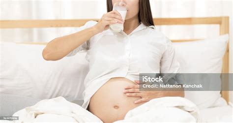 닫기 최대의 A 임신 여자 신선한 우유 또는 물 유리를 손으로 그녀의 배꼽을만 지 큰 배와 함께 행복 한 여자입니다 임신 및 모성 순간 사람과 기대 개념 가족에 대한 스톡