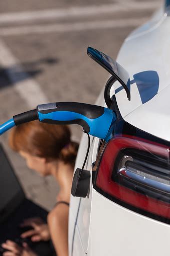 그녀의 전기 자동차가 충전하는 동안 지상에서 기다리고 소녀 랩톱 컴퓨터에서 작업하기 20 24세에 대한 스톡 사진 및 기타 이미지 20 24세 교통수단 급유 Istock