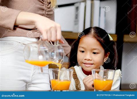 Asian Happy Family Spending Time Together, Mother Pouring Fresh Orange Juice from Jug for Her ...