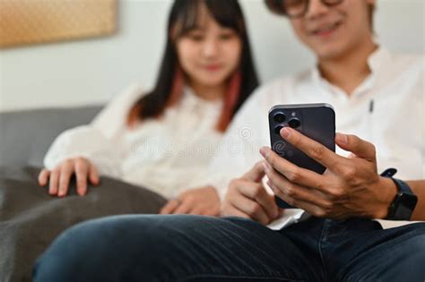 Happy Young Couple Spending Weekend Time On Couch In Living Room And