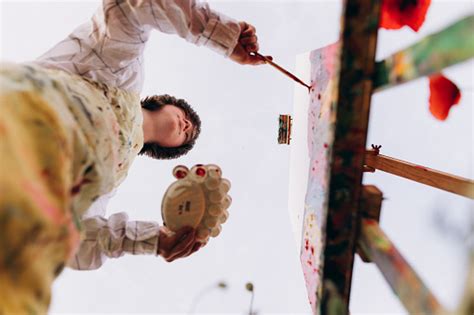 다운 증후군을 앓고있는 소년은 이젤 앞에 서서 들판에서 캔버스에 조심스럽게 그림을 그립니다 Mental Wellbeing에 대한 스톡 사진 및 기타 이미지 Mental