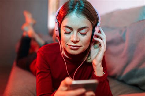 헤드폰에 아름 다운 여자 에 소파에 누워 휴대 전화에 손과 집에서 음악을 듣고 25 29세에 대한 스톡 사진 및 기타 이미지 25 29세 Brand Name Smart