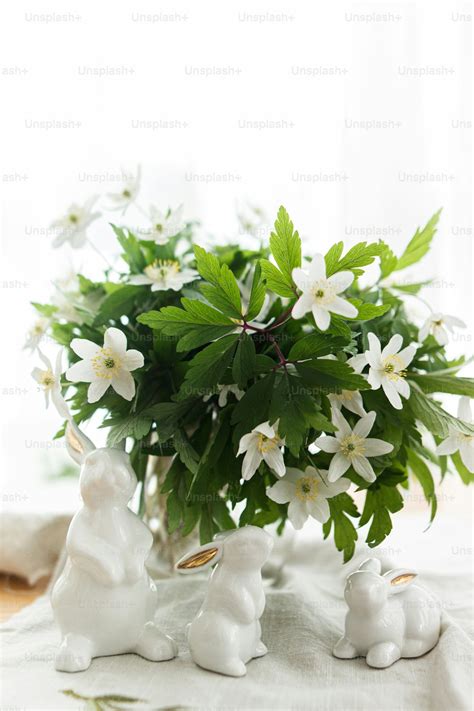 귀여운 흰 토끼와 봄 꽃이 부드러운 빛의 소박한 테이블에 린넨 천 냅킨에 있습니다 행복한 부활절 부활절 사냥 개념입니다 흰 토끼 인형과 피는 아네모네 꽃 시골 정물