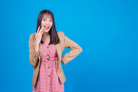 흥분 아시아 긍정적 인 사업가는 고립 된 파란색 배경 위에 복사 공간을 유지하면서 입에 손을 잡고 정장을 착용쾌한 성공적인 직업 좋은 에너지 개념 25 29세에 대한 스톡