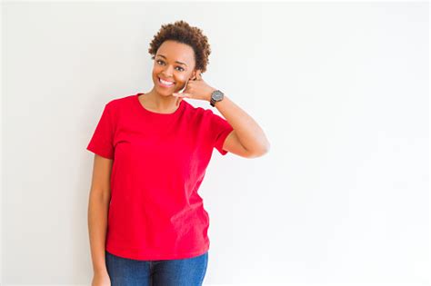 젊은 아름다운 아프리카 계 미국인 여성 위에 흰색 배경 미소 전화에 얘기 처럼 손과 손가락으로 전화 제스처를 하 고 개념을 전달합니다 T 셔츠에 대한 스톡 사진 및 기타