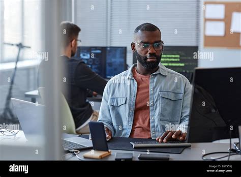 portrait of black man using computer while programming mobile software