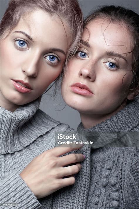 회색 배경에 회색 스웨터를 입은 두 명의 젊은 여성 포옹으로 손을 앞으로 뻗는 아름다운 소녀들 여성 우정 개념 2명에 대한 스톡 사진 및 기타 이미지 Istock