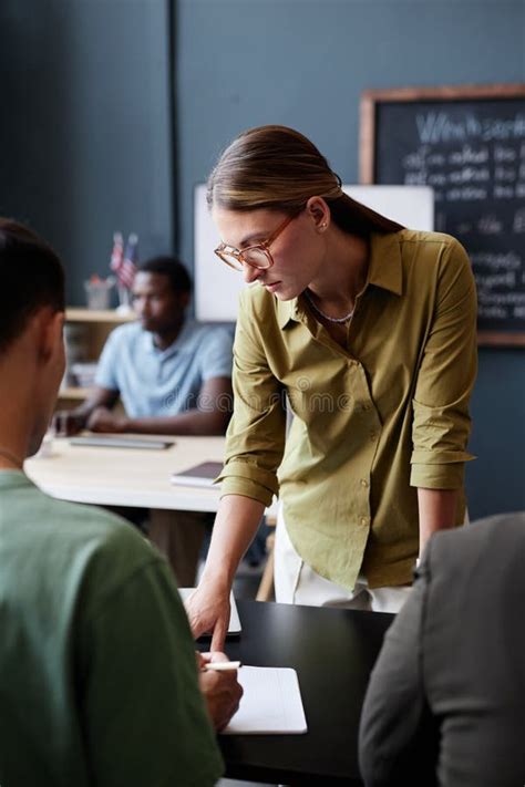Female English Instructor Helping Student With Task In Class At School