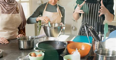 줄무늬 앞치마를 입은 젊은 남성 요리 코치가 부엌에서 직장에 서서 맛있는 음식을 요리하는 방법을 설명하는 학습자 그룹 사진 Unsplash의 스테인리스 이미지