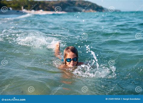 Boy Of 8 Years Old Swims In The Sea In Blue Swimming Goggles In The
