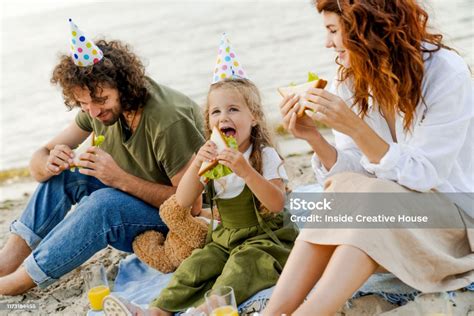 해변에서 샌드위치를 먹는 파티 모자를 가진 가족 야외에서 간식으로 딸의 생일을 즐기는 가족 샌드위치 음식에 대한 스톡 사진 및 기타 이미지 Istock