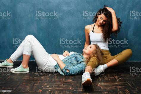 젊은 예쁜 십대 소녀 친구 금발과 갈색 머리 곱슬 머리 포즈 명랑 한 에 블루 배경 라이프 스타일 사람들 개념 2명에 대한 스톡 사진 및 기타 이미지 Istock