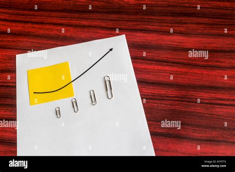 Curve Graph Printed On A Sheet Of Paper And Yellow Note With Arranged By Size Paper Clips Stock
