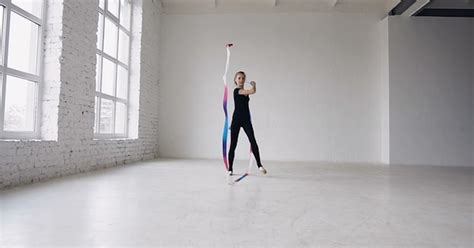 Светловолосая девочка подросток танцует художественную гимнастику современная с цветной лентой