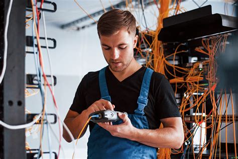 측정 장치와 유니폼을 입은 젊은 남자는 서버 룸에서 인터넷 장비 및 전선과 함께 작동합니다 25 29세에 대한 스톡 사진 및 기타 이미지 Istock