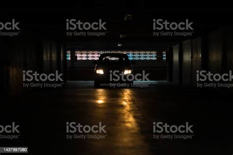 어두운 차고에서 헤드라이트가 켜진 자동차 조명이 켜진 작은 차의 실루엣 자동차의 헤드 라이트로 조명 된 어두운 차고 반짝이는에