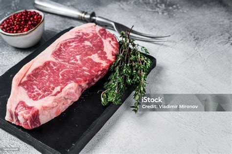 대리석 보드에 원시 스트립 또는 뉴욕 스트립 스테이크 흰색 배경입니다 맨 위 보기입니다 복사 공간 0명에 대한 스톡 사진 및