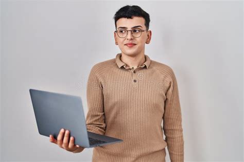 non binary person using computer laptop smiling looking to the side and