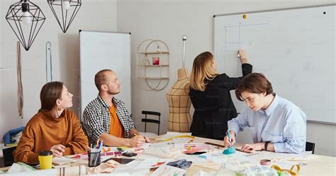 젊은 창조적 인 사람들이 테이블에 앉아 있고 수석 디자이너가 보드에 패턴을 그리는 동안 사진 Unsplash의 혁신 이미지