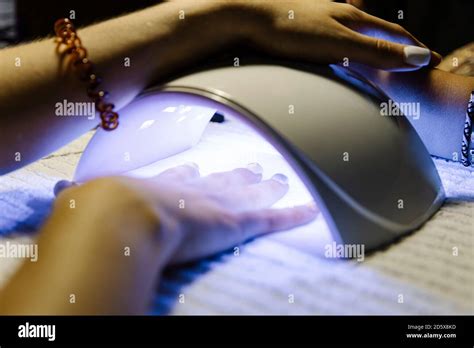 Unrecognizable Female Client Holding Hand Under UV Lamp During Manicure Procedure In Salon Stock