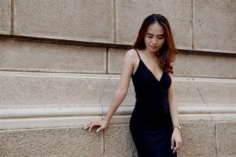 Premium Photo A Woman In A Black Dress Stands In Front Of A Stone Wall