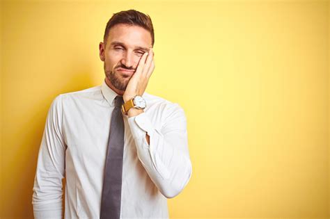 노란색 고립 된 배경 에 우아한 흰색 셔츠를 입고 젊은 잘 생긴 사업가 는 피곤하고 교차 팔우울증 문제로 지루 찾고 생각