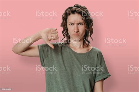 젊은 곱슬 머리 여자 찡그린 얼굴 불쾌 한 제공 엄지 손가락 아래로 제스처 엄지손가락을 아래로에 대한 스톡 사진 및 기타 이미지 엄지손가락을 아래로 개념 곱슬 머리