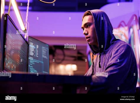 Asian Hacker In Hood Installing Spyware On Victim Computer And Coding
