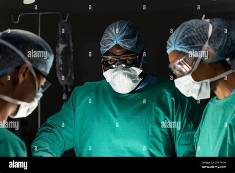 Diverse Male And Female Surgeons Operating On Patient In Operating Theatre At Hospital Stock