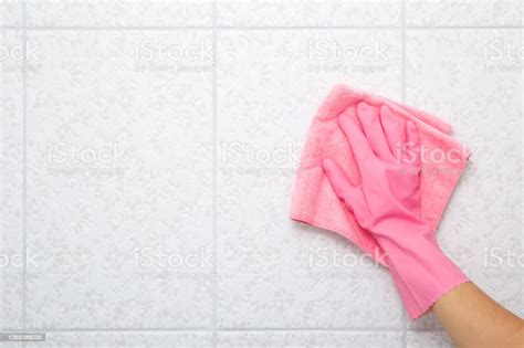 분홍색 고무 보호 장갑에 여자 손 은 마른 걸레와 밝은 회색 세라믹 타일 벽을 닦아 근접 촬영 봄 일반 또는 정기적 인 청소 텍스트 또는 로고의 빈 장소입니다 더러운에 대한