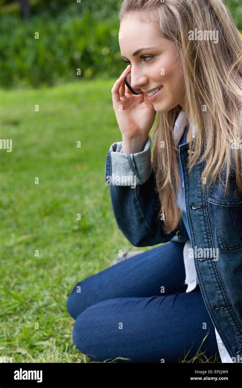 Young Smiling Girl Talking On The Phone While Sitting On The Grass