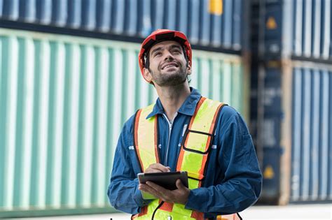 남성 작업자는 컨테이너 화물 현장에서 디지털 태블릿으로 작업하고 컨테이너 상자를 적재하고 상품을 적재하고 컨테이너를 점검하고 컨테이너를 선적합니다 화물 물류 및 운송 개념
