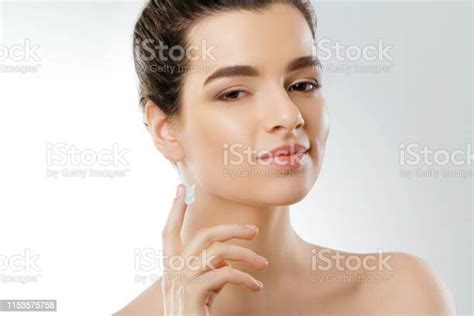 페이셜 케어 크림을 바르고 웃는 여자 피부에 화장품 크림을 가진 젊은 여자의 초상화입니다 부드러운 피부에 미용 제품과 아름 다운 여자의 근접 촬영 얼굴을 만지고 자연