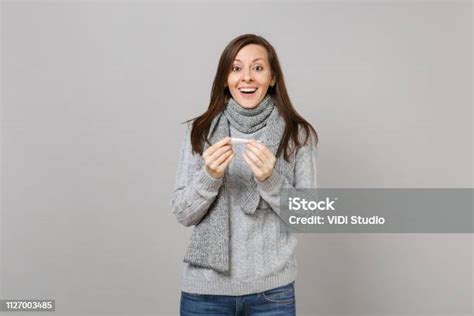 스튜디오에서 회색 벽 배경에 고립 된 온도계를 들고 회색 스웨터 스카프에 즐거운 흥분된 젊은 여자 건강 한 라이프 스타일 아픈 아픈 질병 치료 추운 계절 개념 복사 공간을