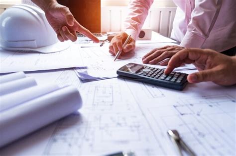 Premium Photo Midsection Of Colleagues Analyzing Blueprints On Table