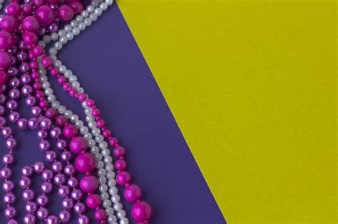 마디 그라 또는 지방 화요일 구성 노란색과 보라색 종이 배경에 여러 가지 색상의 마디 그라 구슬 평평한 평지 텍스트 공간을