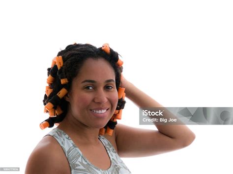 젊은 아름 다운 성인 여성 머리 샷 섞인 아프리카계 미국인 여자를 팔꿈치와 함께 웃 고 오렌지 컬러 또는 롤러에 흰색 배경으로 고립 된 그녀의 검은 머리에 회색 탱크 톱