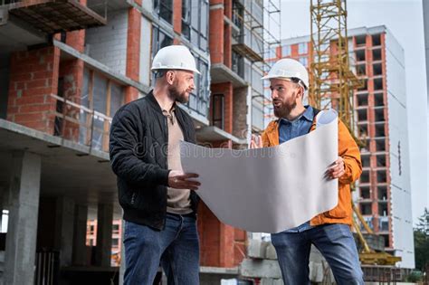 Man Discussing Building Plan With Architect At Construction Site Stock