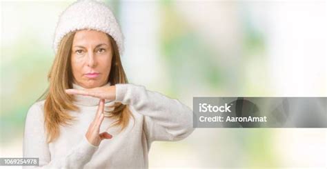 격리 된 배경 손으로 좌절 하 고 시간이 초과 제스처와 심각한 얼굴 겨울 스웨터와 모자를 입고 아름 다운 중 년 여자 갈색