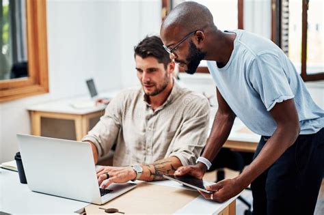 Let Me See If I Can Help A Handsome Young Businessman Helping A Male Colleague In The Office