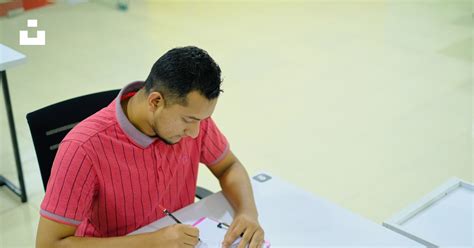 빨간색과 흰색 줄무늬 크루넥 티셔츠를 입은 남자가 흰 종이에 글을 쓰고 있다 사진 Unsplash의 무료 사무실 이미지