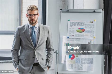 양복과 안경 주머니에 손을와 서 하 고 사무실에서 카메라 보고 잘생긴 젊은 사업가 경영자에 대한 스톡 사진 및 기타 이미지 경영자 그래프 기업 비즈니스 Istock